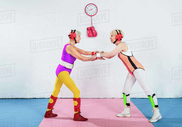 Side view of senior female wrestlers in head protection fighting and ...