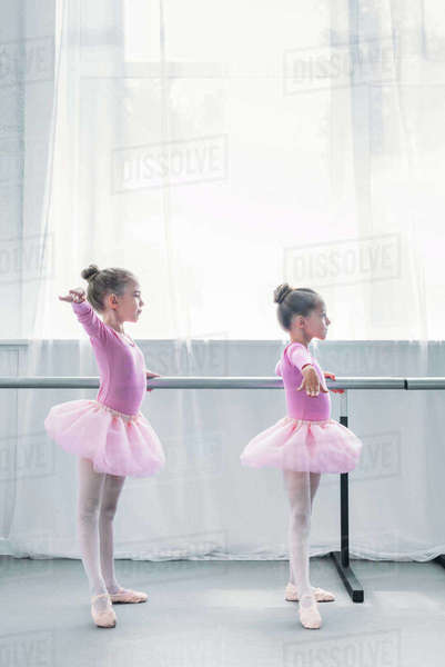 Side view of cute small ballet dancers exercising in ballet school ...