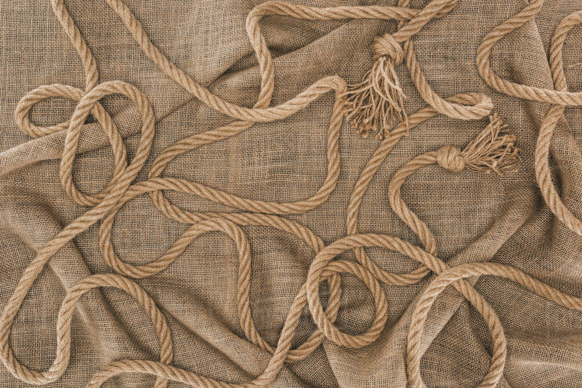 Top view of arranged brown nautical rope with knots on sackcloth ...