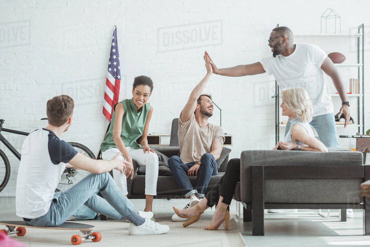 Group of young people talking to each other and smiling African ...