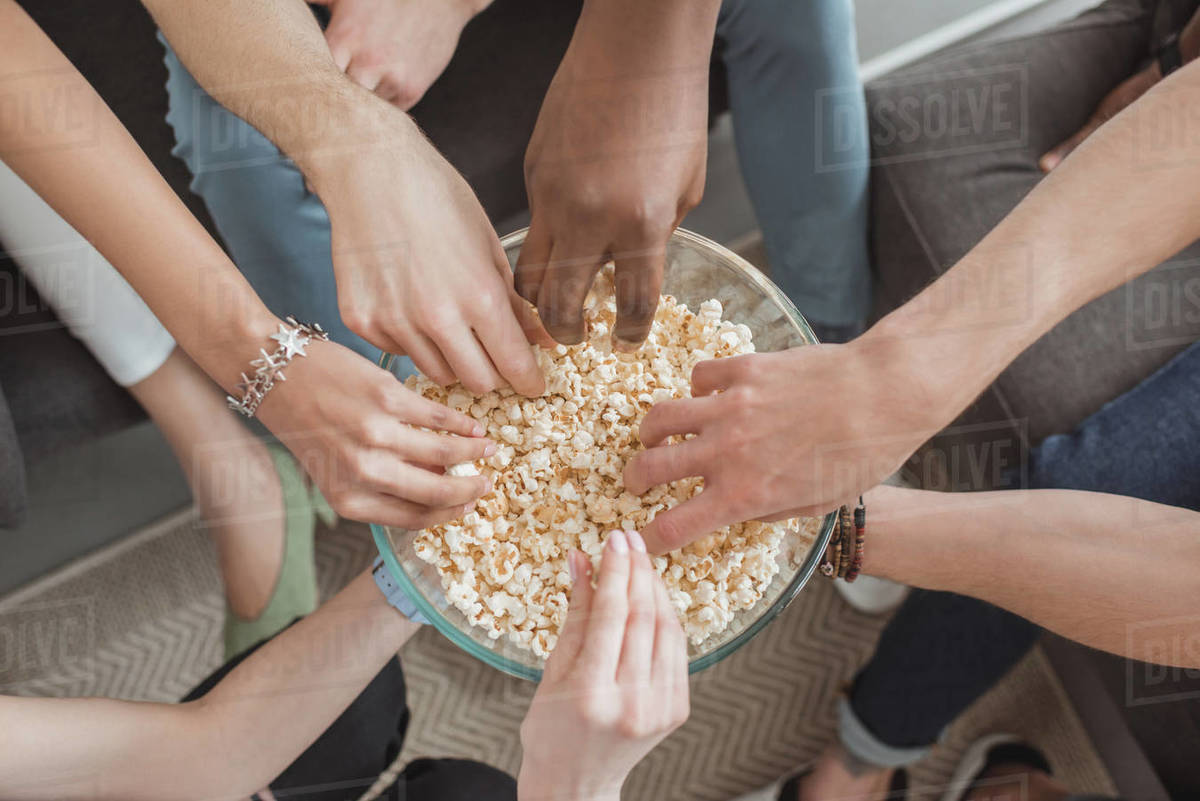 Top view of female and male hands taking popcorn from bowl - Royalty ...