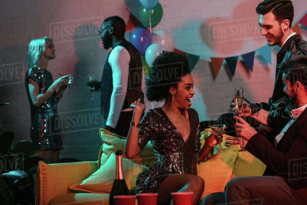 Cheerful young people enjoying drinks at talking at party - Royalty ...