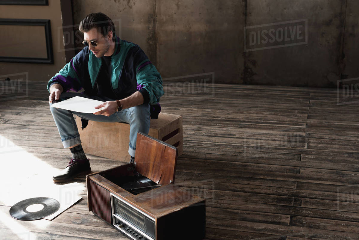 Thoughtful nostalgic man in vintage windcheater with vinyl record ...