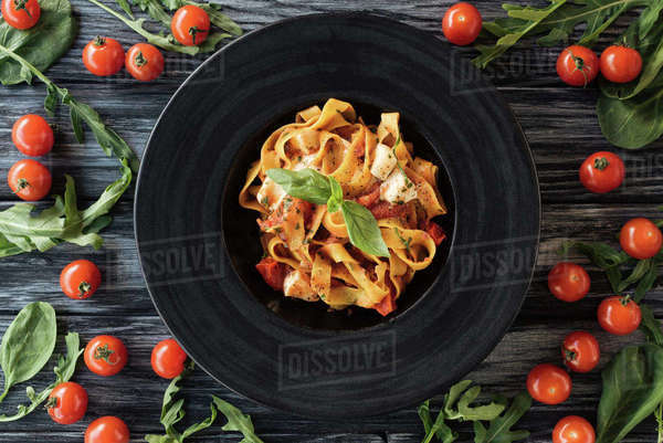 Top view of delicious pasta on plate and fresh vegetables on wooden ...
