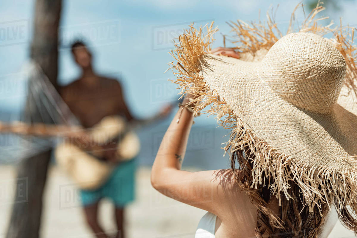Selective focus of girl in straw hat and man playing acoustic guitar ...