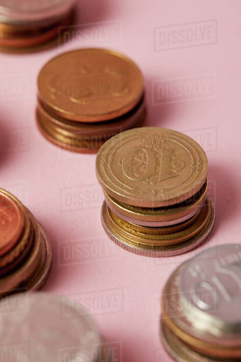 Close-up shot of stacks of different coins on pink - Stock Photo - Dissolve