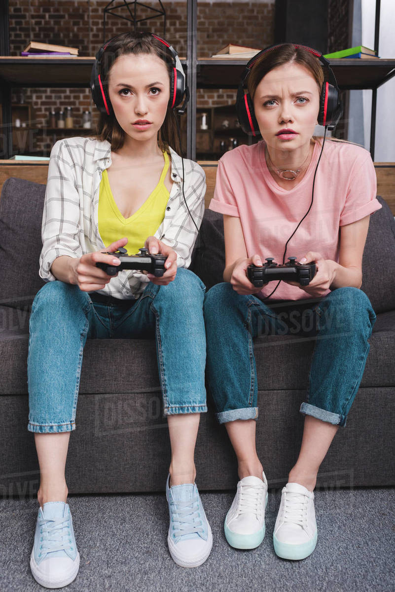 concentrated female friends in headphones with joysticks in hands ...