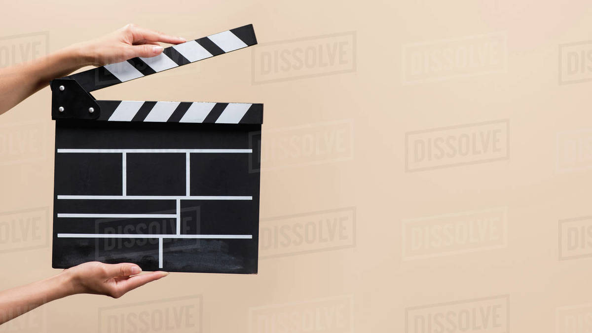 Partial view of woman holding clapper board in hands isolated on beige ...