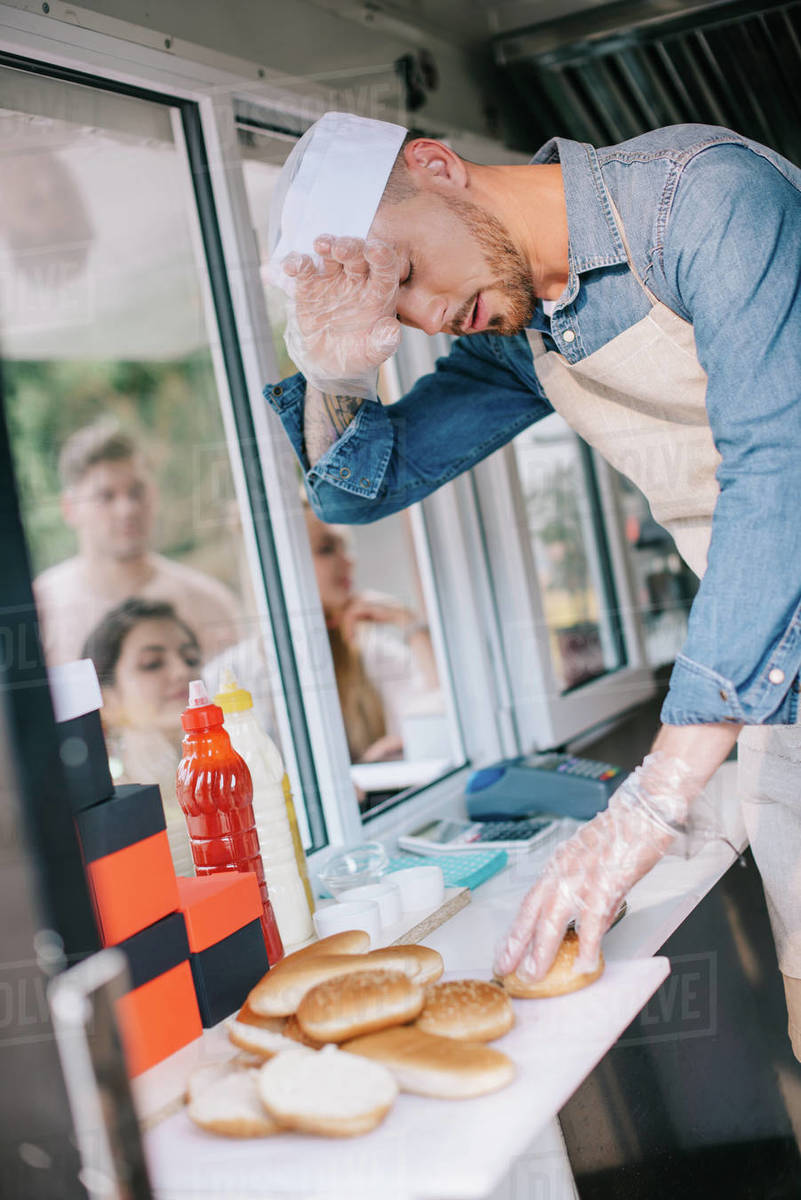 Tired chef working in food truck while customers waiting outside ...