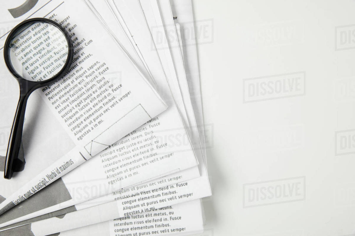 Top view of magnifying glass and newspapers on grey, information ...