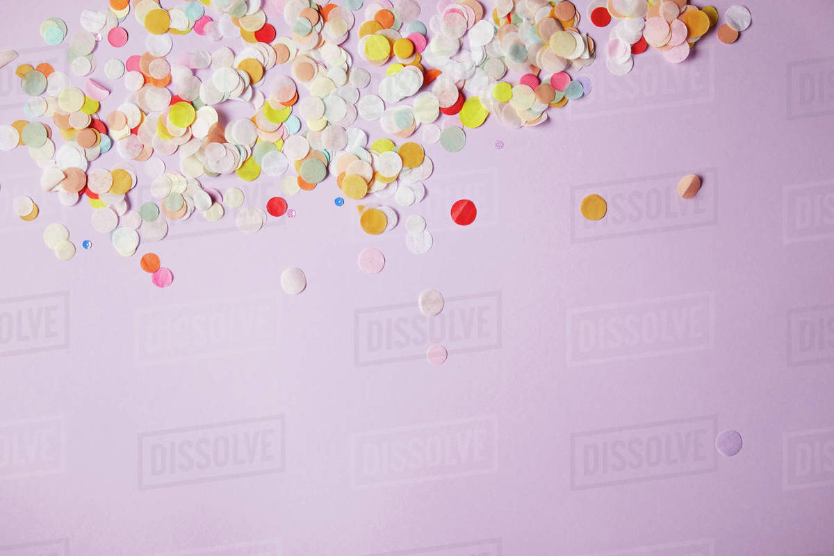 Top view of tiny confetti pieces on violet surface - Stock Photo - Dissolve