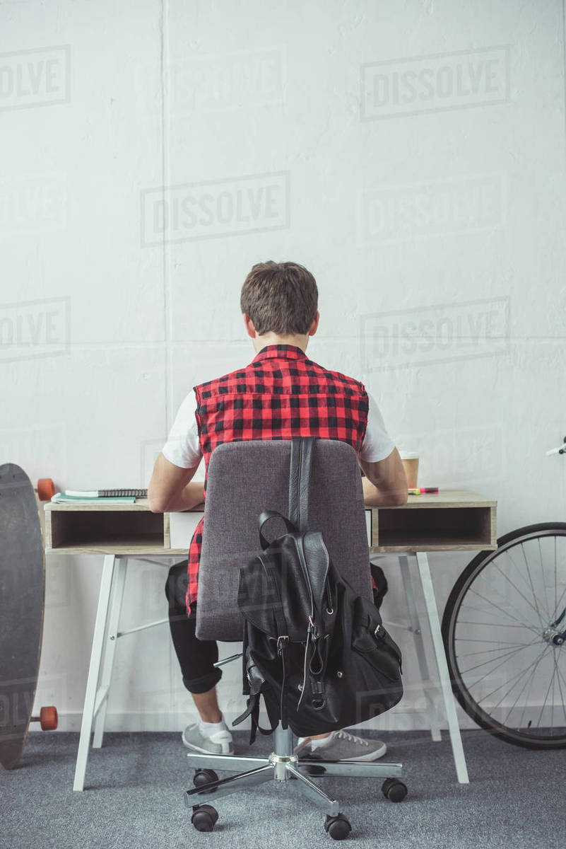 Back view of male student doing homework at table - Royalty-free Stock ...