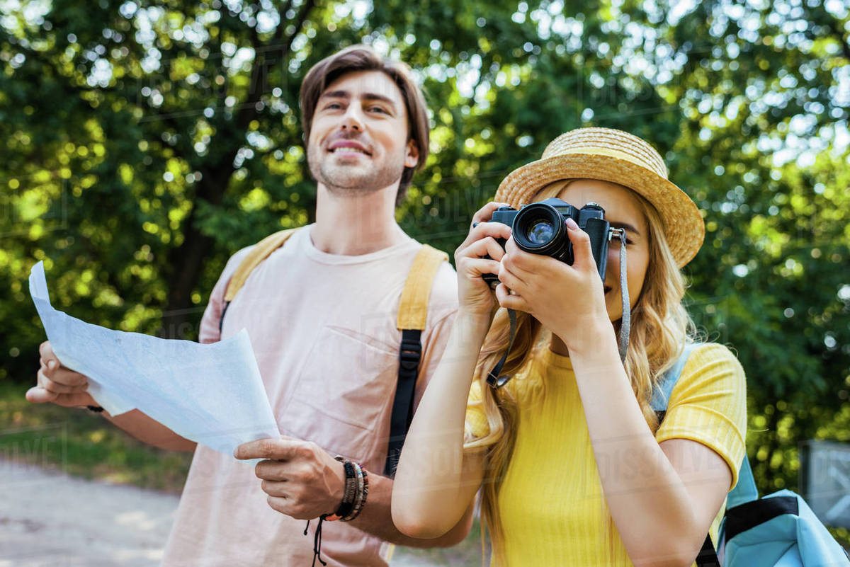 Portrait of couple of tourists with map and photo camera in park ...
