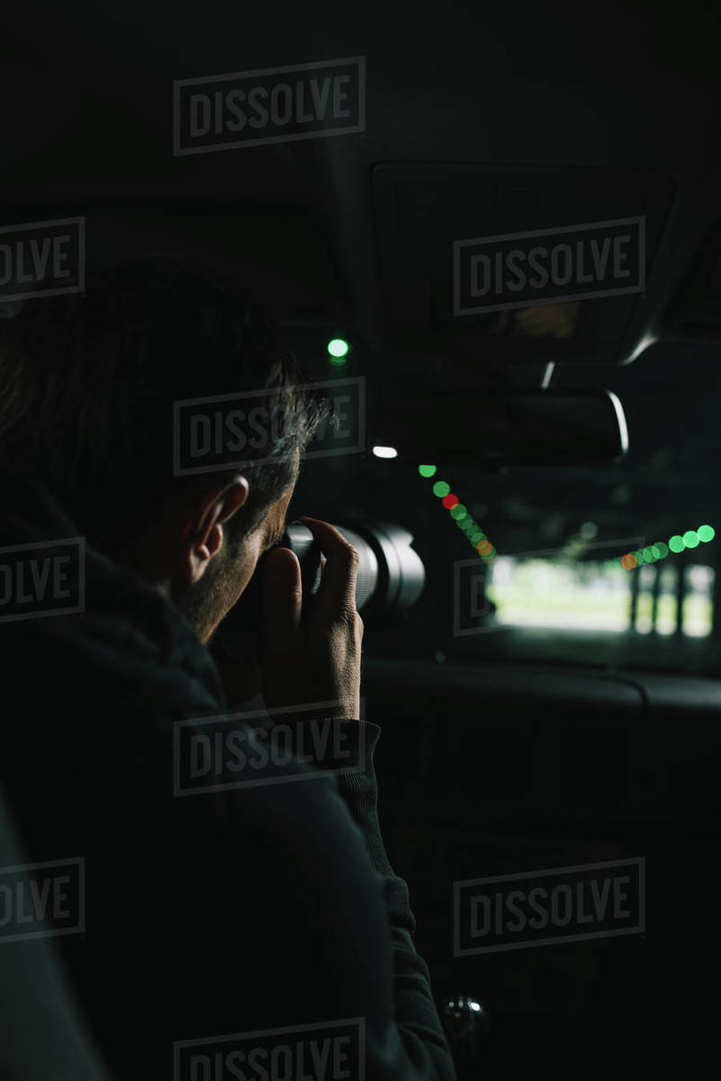 Rear view of man doing surveillance by camera with object glass from ...