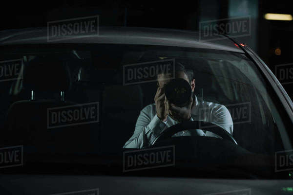 Front view of male private detective spying by camera with object glass ...