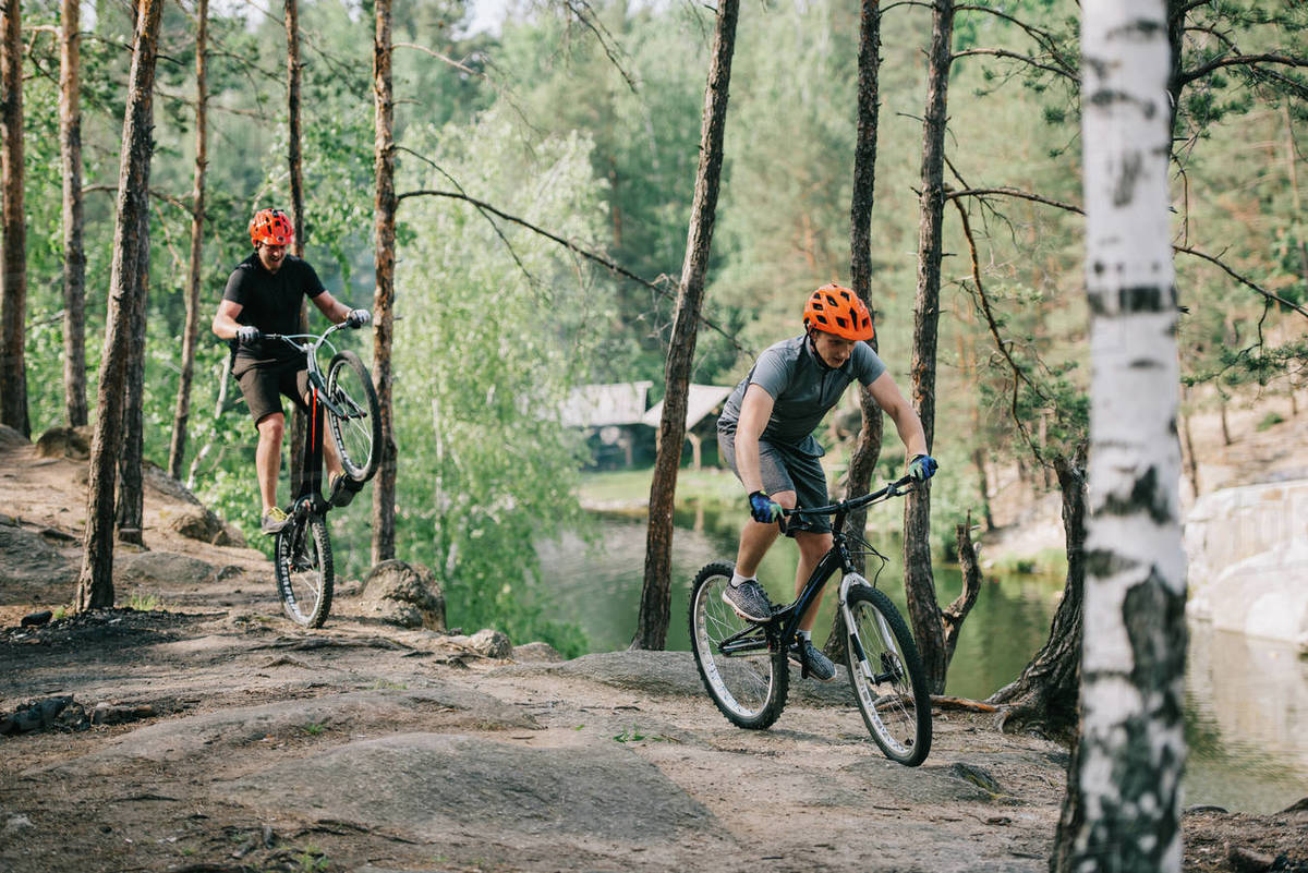 Male extreme cyclist in protective helmet balancing on back wheel of ...