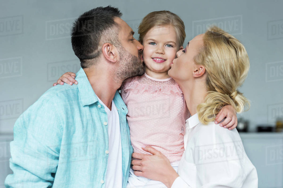 Happy parents kissing adorable little daughter at home - Royalty-free ...