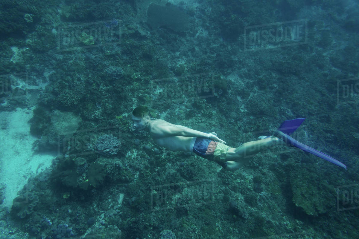 Side view of young man in flippers diving in ocean alone - Royalty-free ...