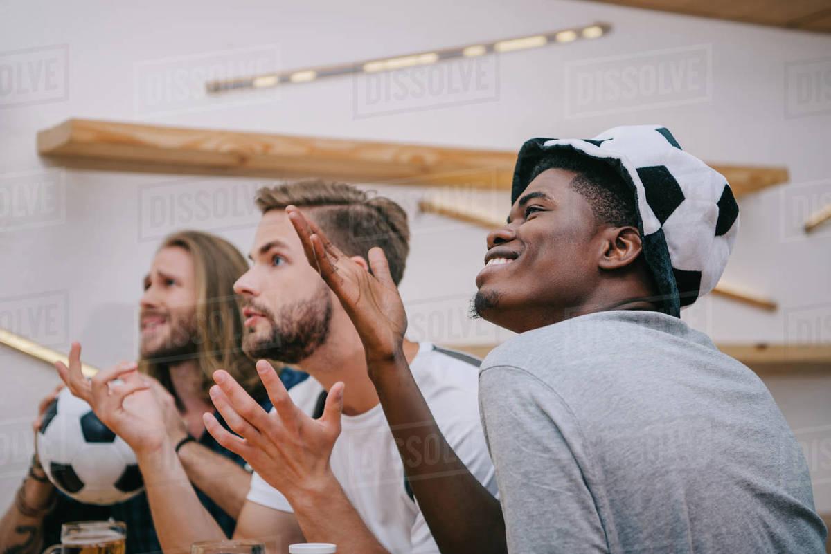 Side view of multicultural group of male football fans gesturing by ...