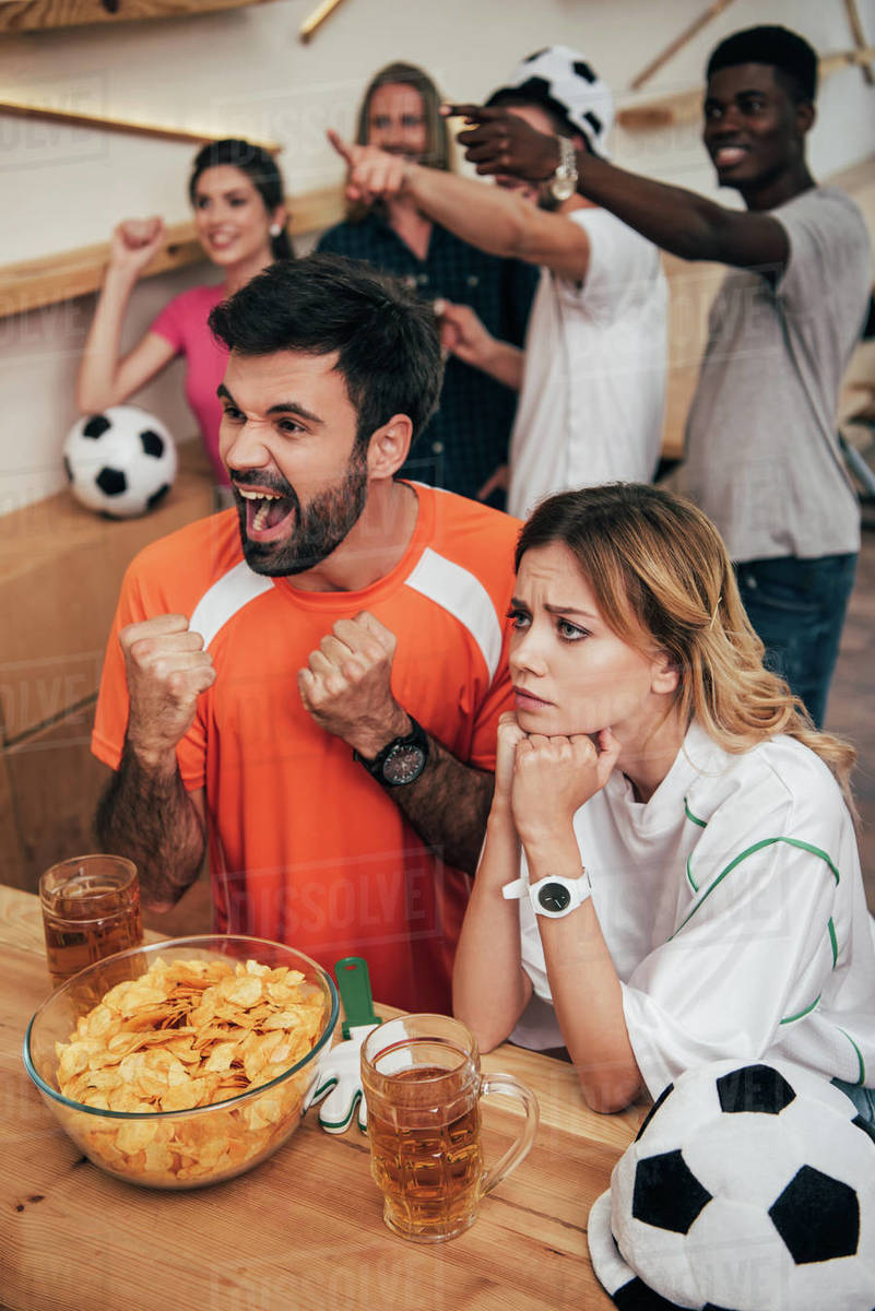 Emotional multicultural football fans pointing by fingers and watching ...