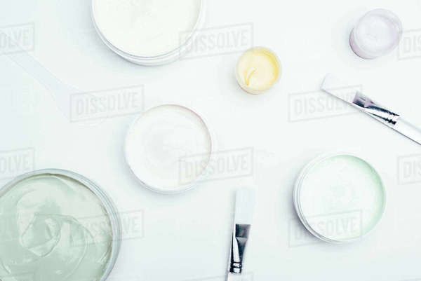 Flat lay with different clay masks in containers and brushes isolated ...