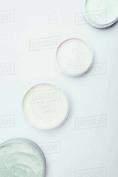 Flat lay with different clay masks in containers placed in row isolated ...