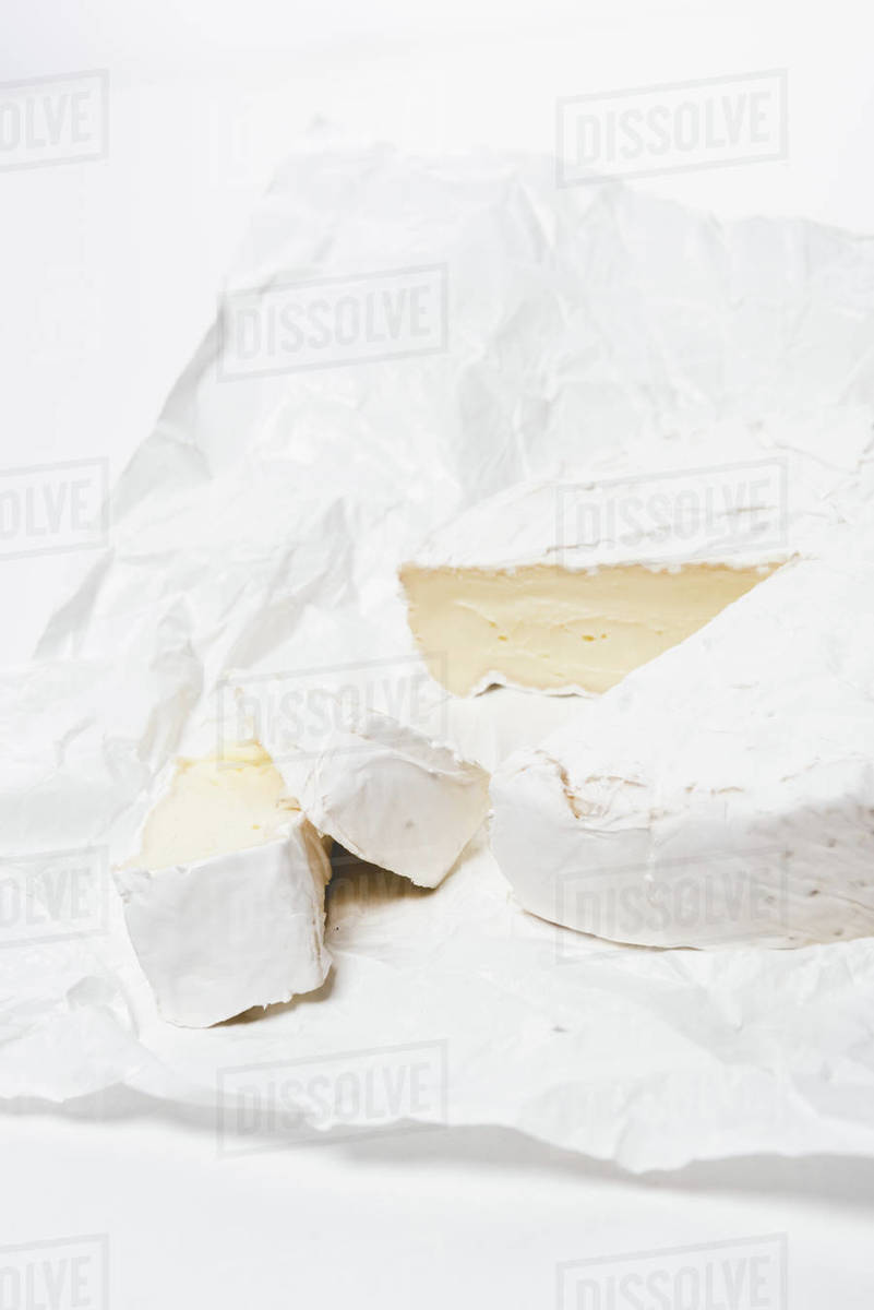 Close-up shot of sliced brie cheese on crumpled paper and on white ...