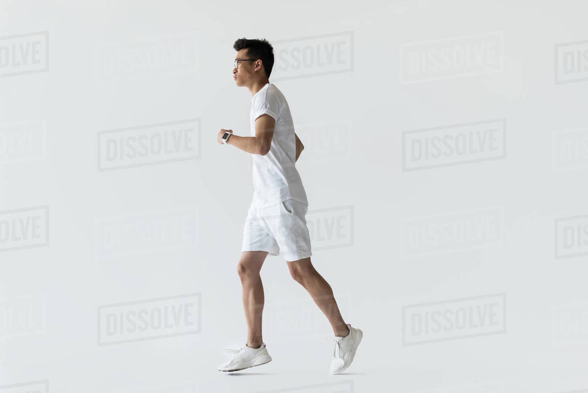 side view of young asian sportsman running on grey background - Royalty ...