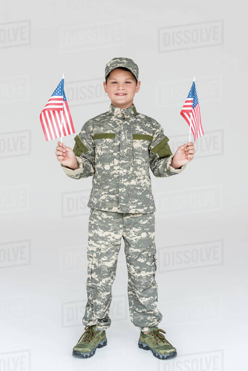 smiling child in military uniform with american flagpoles in hands ...