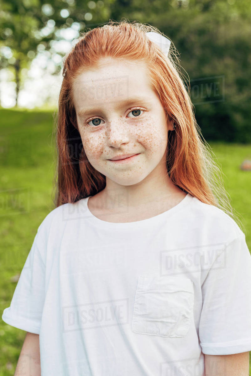 portrait of adorable red haired child smiling at camera in park - Stock ...