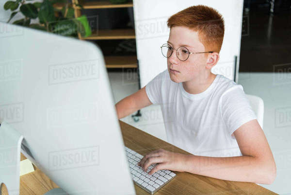 preteen ginger hair boy using computer in room - Stock Photo - Dissolve