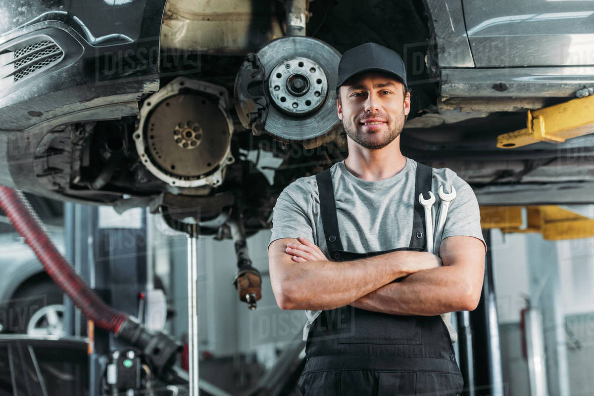 Smiling workman posing with crossed arms in auto mechanic shop - Stock ...