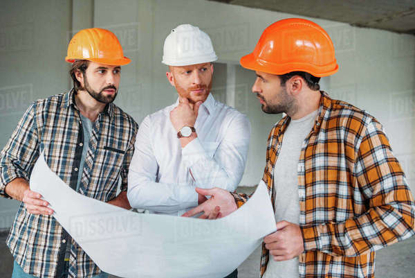 Group of handsome architects with blueprint having conversation inside ...