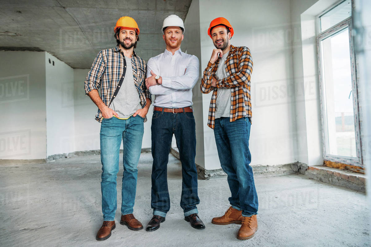 Group of architects inside of constructing building looking at camera ...