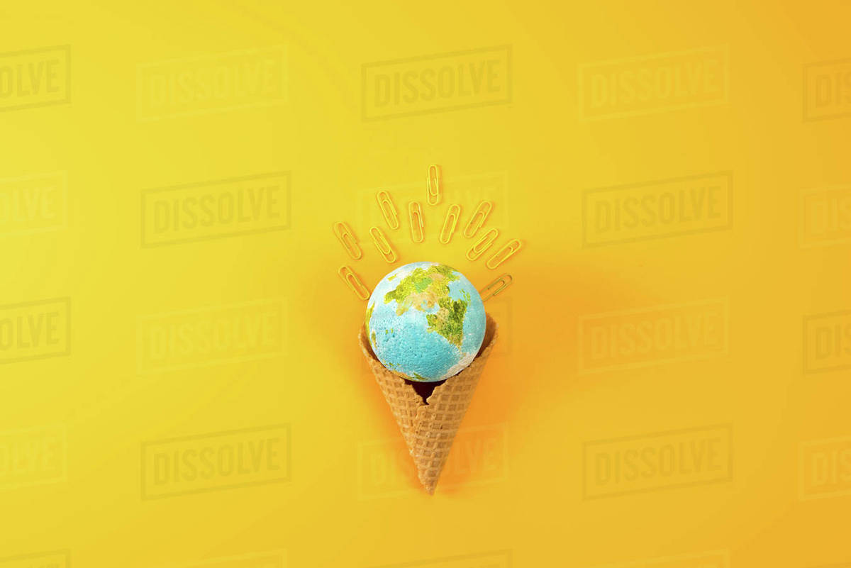 top view of earth globe in waffle cone with paper clips on yellow ...
