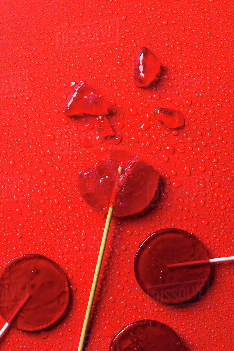 top view of lollipops on red surface with water drops - Royalty-free ...