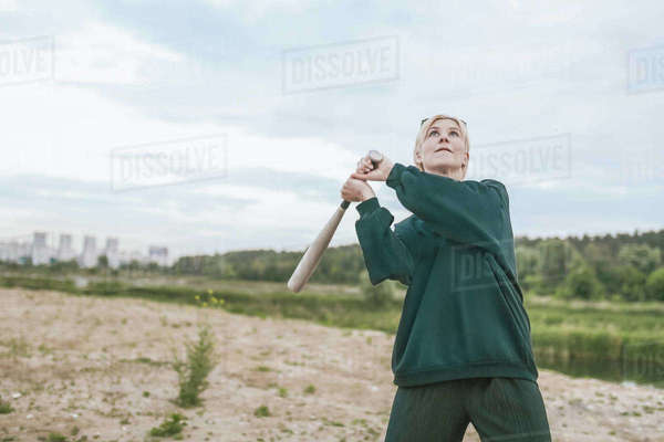 beautiful blonde woman playing with baseball bat and looking up at ...