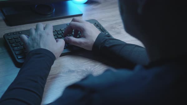 Behind the shoulder shot of a man typing on a keyboard at night. - 4K ...