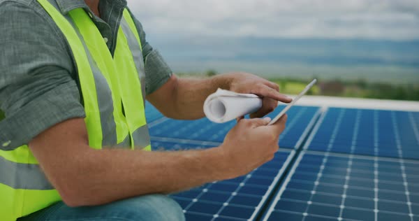 Solar panel technician working with solar panels, looking at blueprints ...