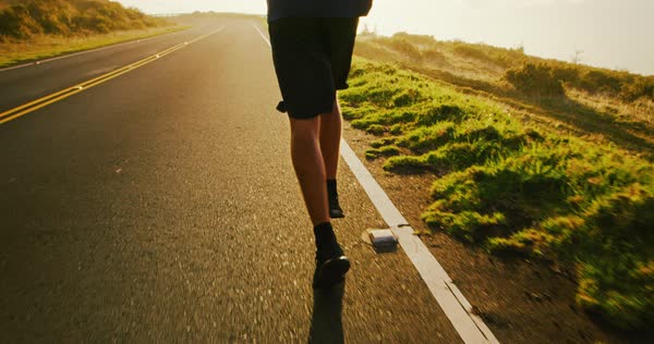 Close up of athletic young man running on the road at sunset - 4K ...