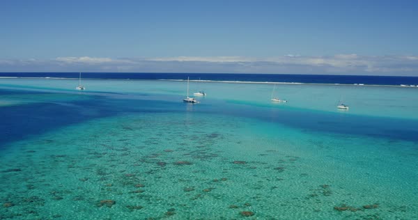 Aerial view of calm island lagoon with light and dark blue water hues ...