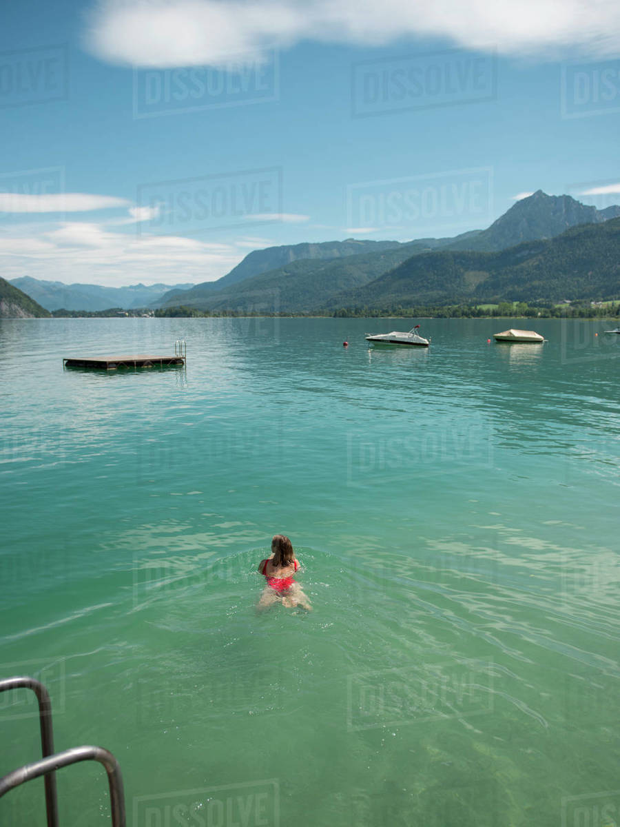 Female swimmer floating in mountain lake - Stock Photo - Dissolve