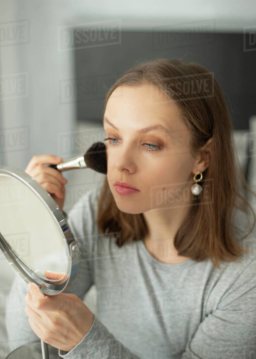 Woman holding makeup brush applying makeup on her face - Stock Photo ...