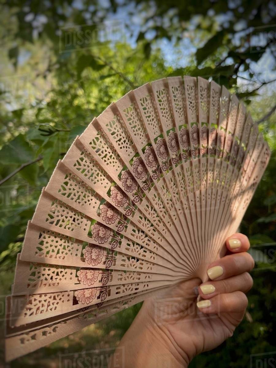 Close-up of a woman's hand holding a fan in a summer garden - Royalty ...