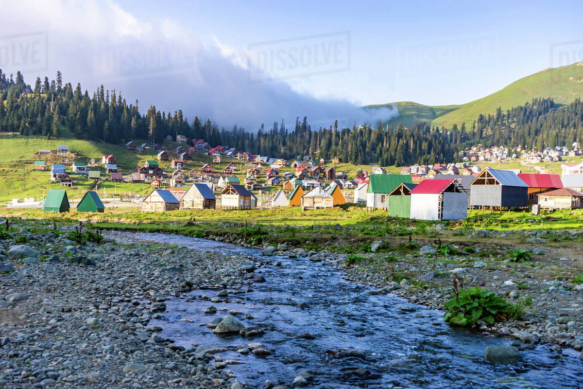 Traditional village houses in the Caucasus mountains by a river ...