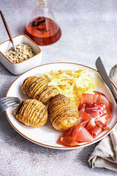 Close-Up of a plate of Hasselback potatoes with fermented cabbage salad ...