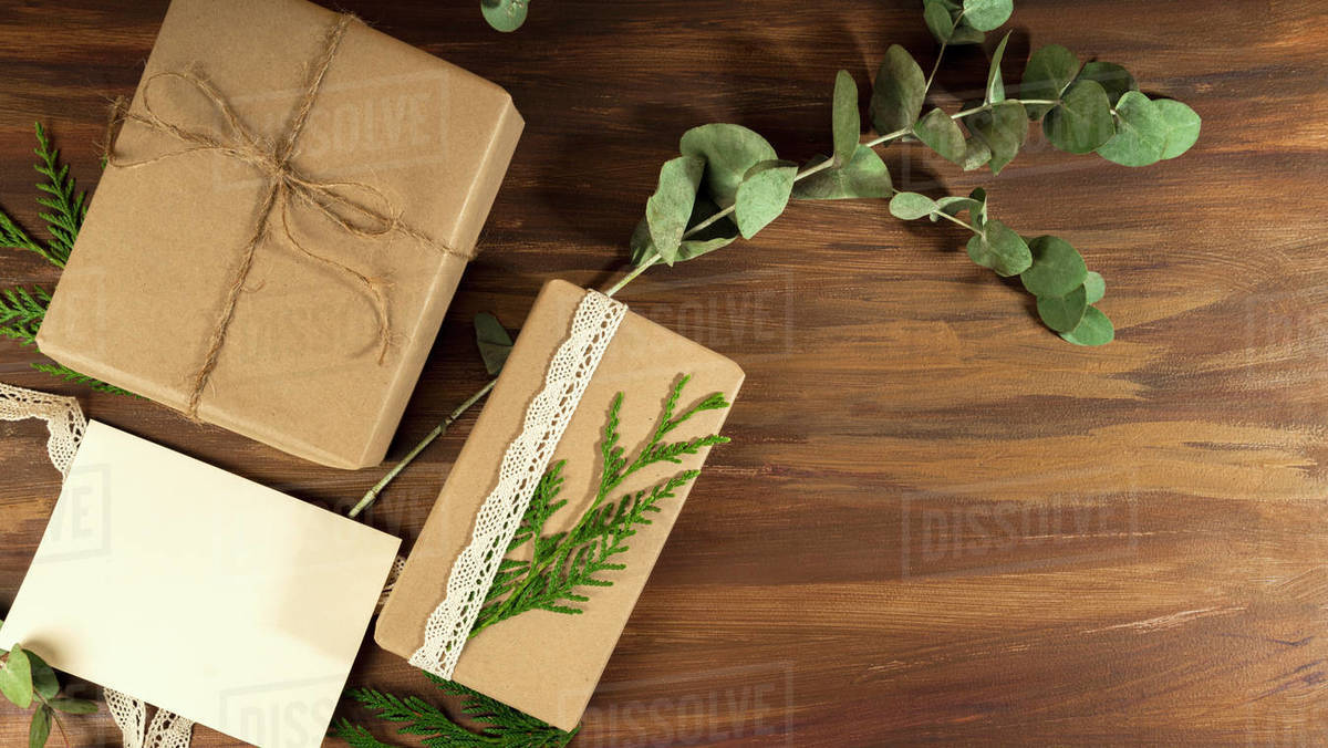 Overhead view of two rustic wrapped gift boxes on a wooden table with a ...