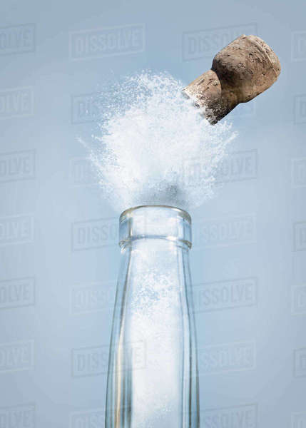 Close-up of liquid and a cork exploding out of a long neck bottle ...