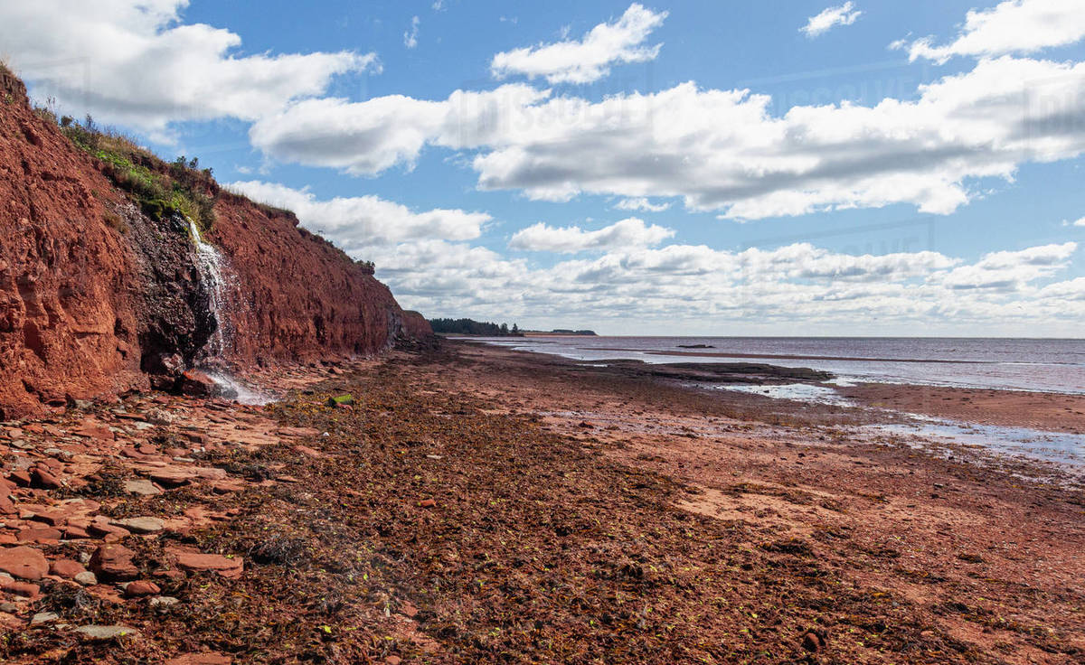 Water pouring over the edge of a cliff onto red clay beach, Prince Edward Island, Canada - Stock ...