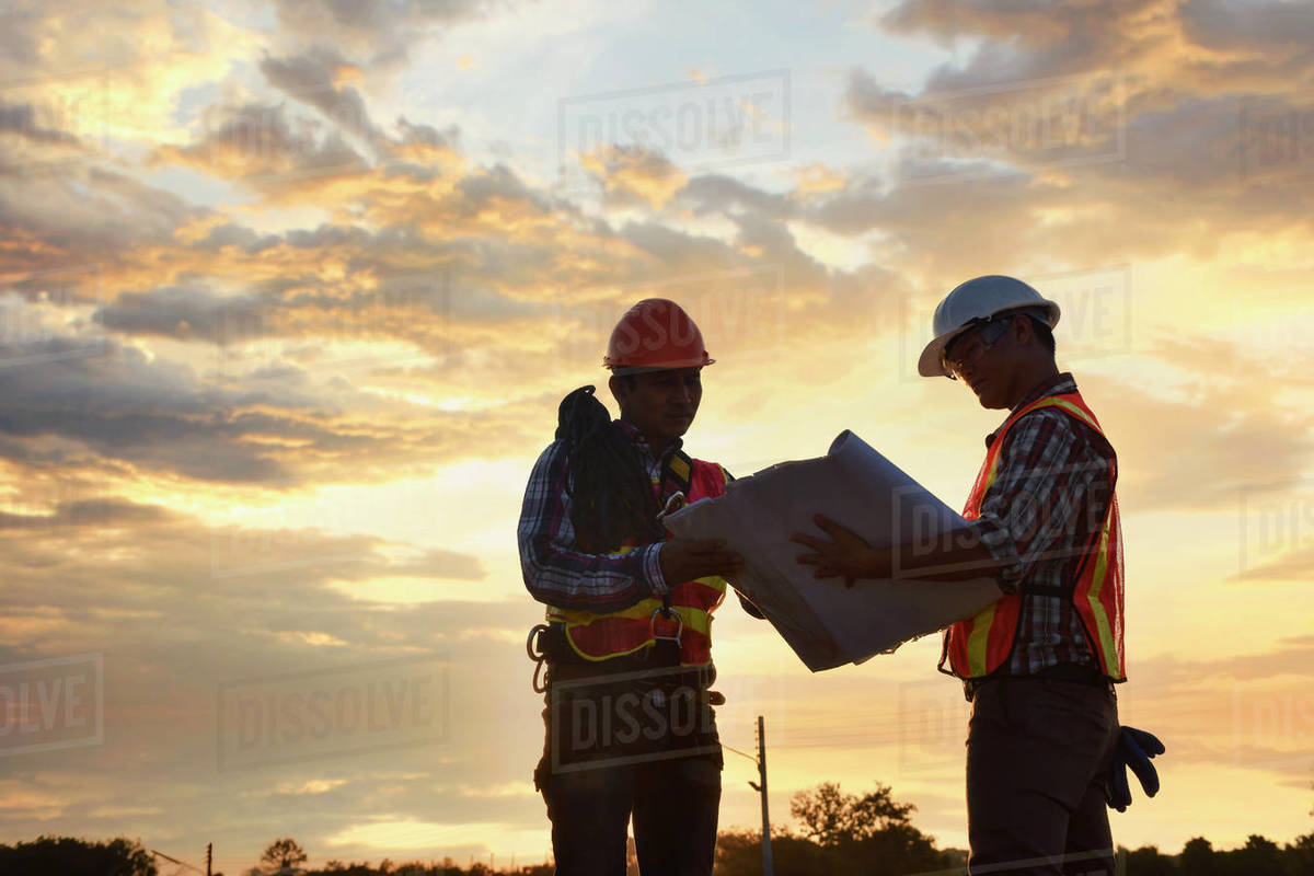 Two construction workers looking at plans on a construction site ...
